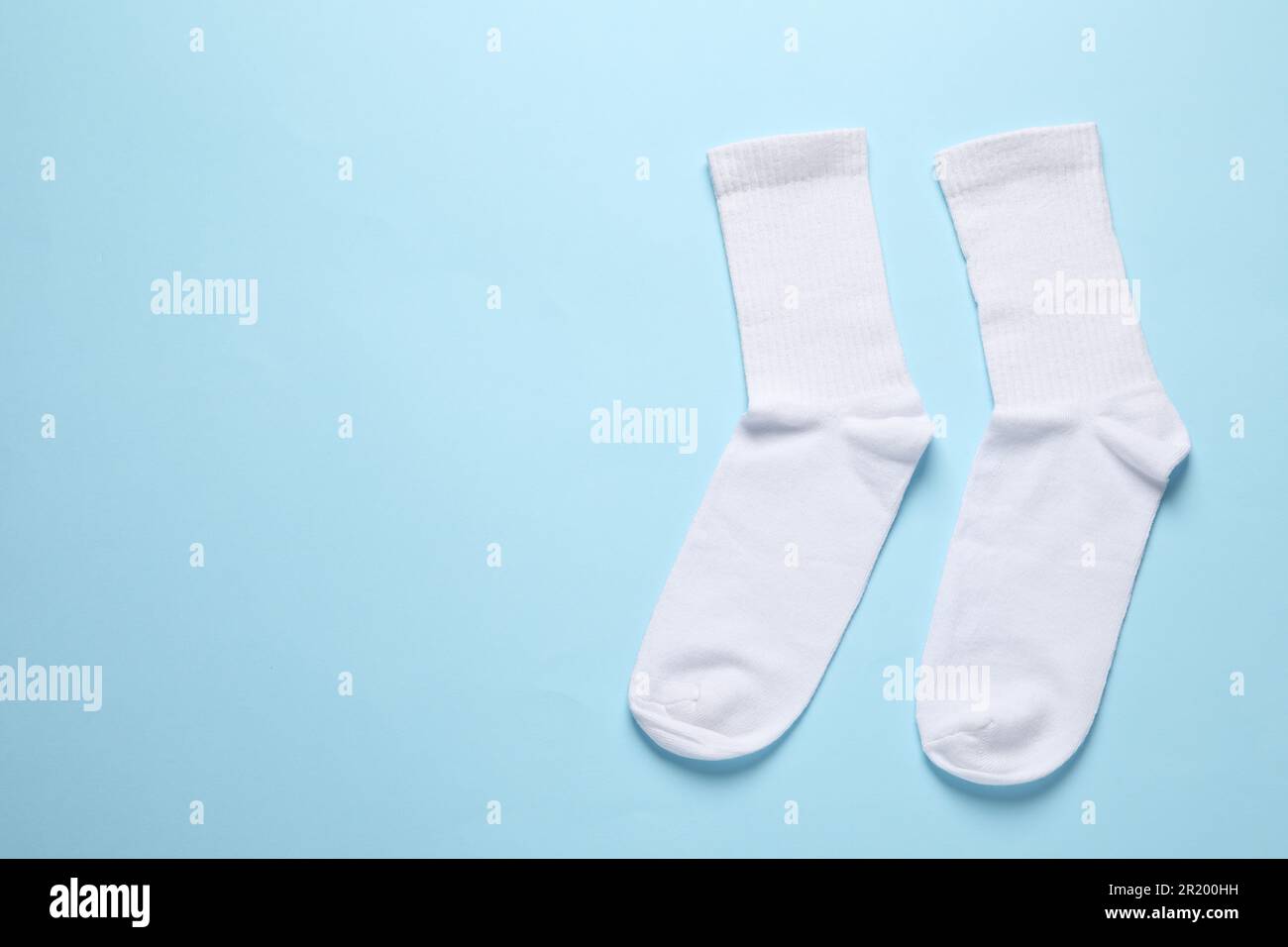 Pair of white socks on light blue background, flat lay. Space for text ...