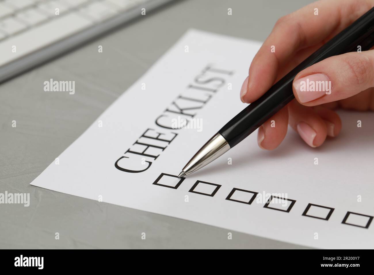 Woman filling Checklist at light grey table, closeup Stock Photo - Alamy
