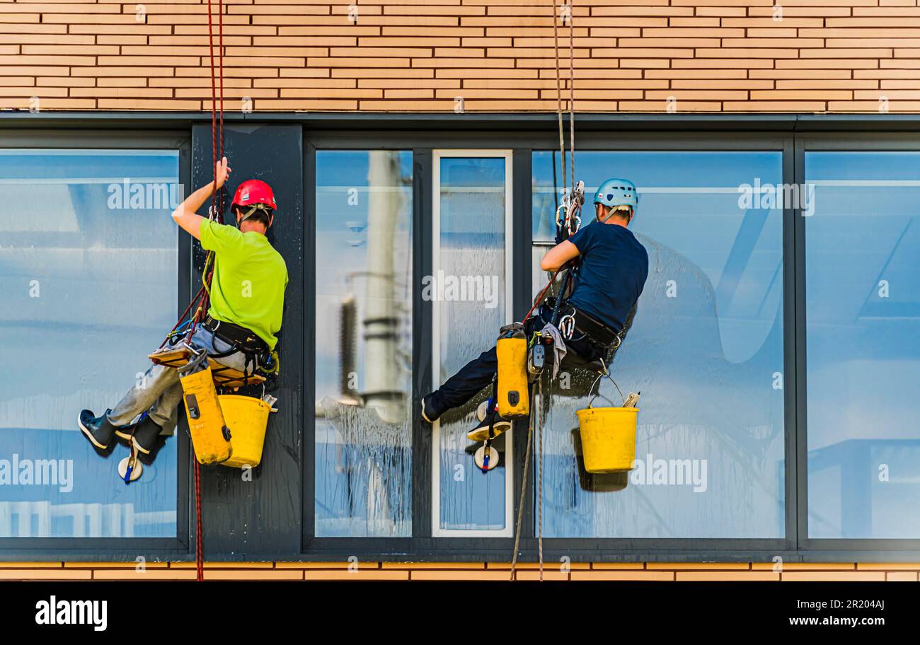 Two men cleaning windows on an office building Stock Photo - Alamy