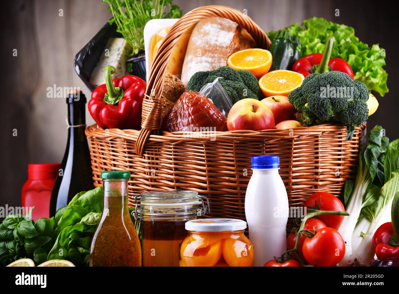 Wicker basket with assorted grocery products including fresh vegetables ...