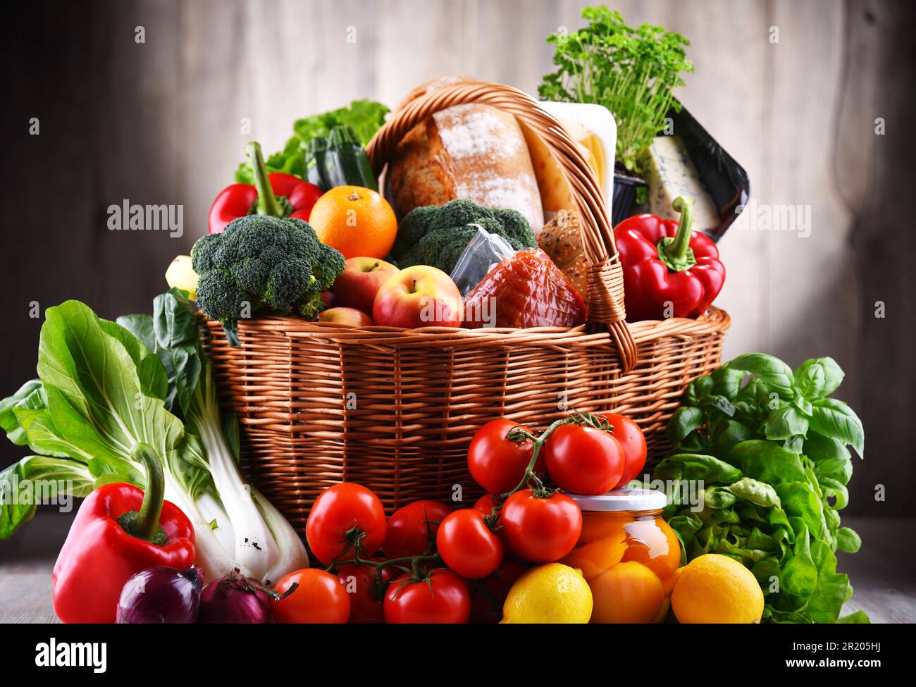 Wicker basket with assorted grocery products including fresh vegetables ...
