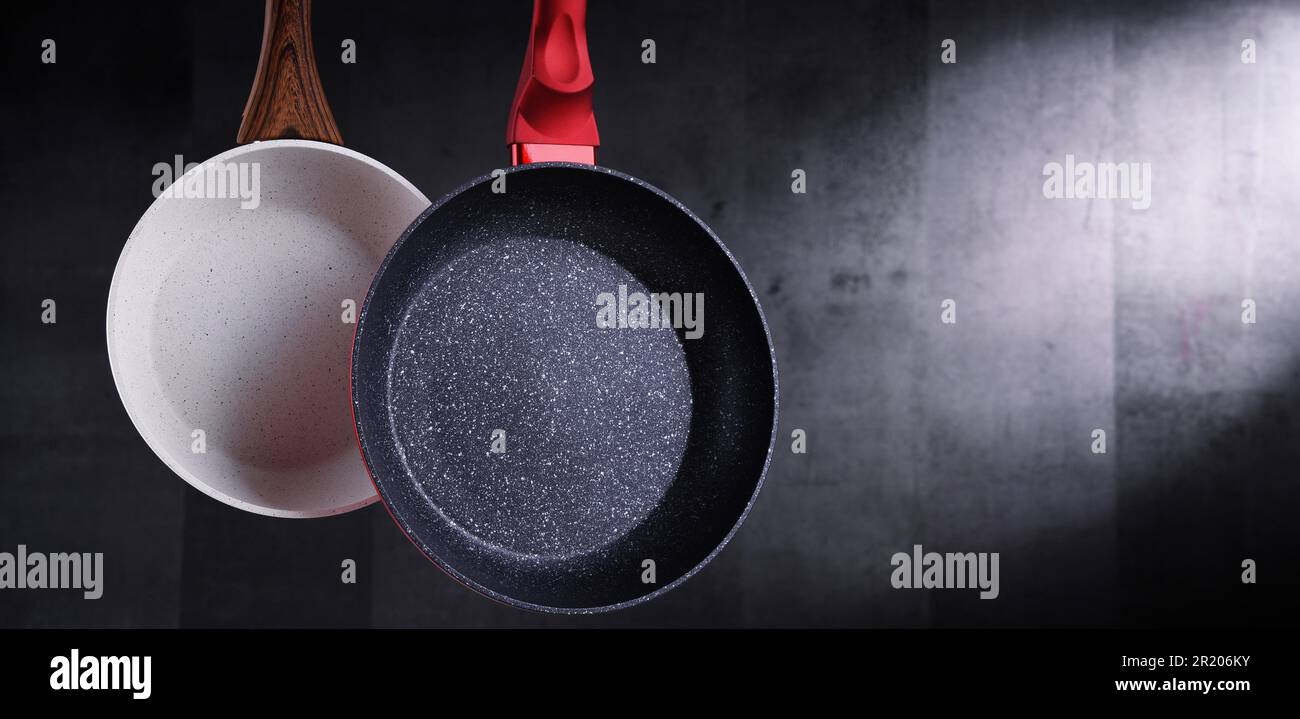 Two hanging stainless frying pans. Kitchen utensils Stock Photo - Alamy