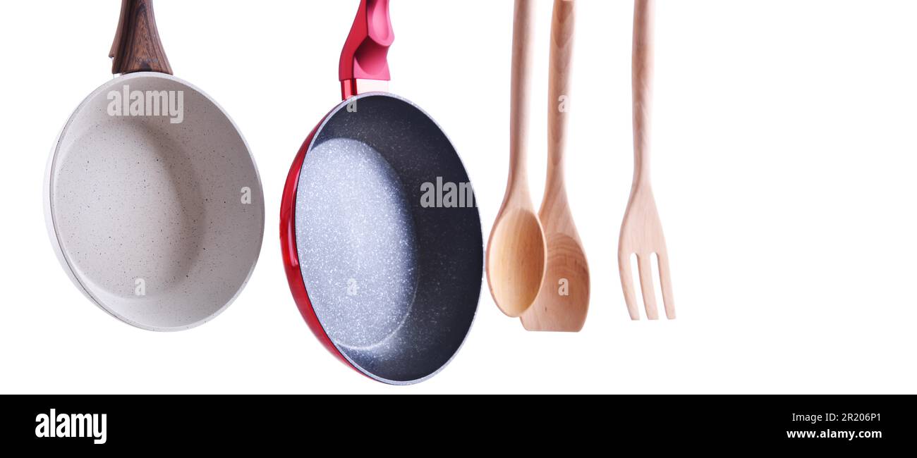 Two hanging frying pans and kitchen utensils isolated on white Stock ...