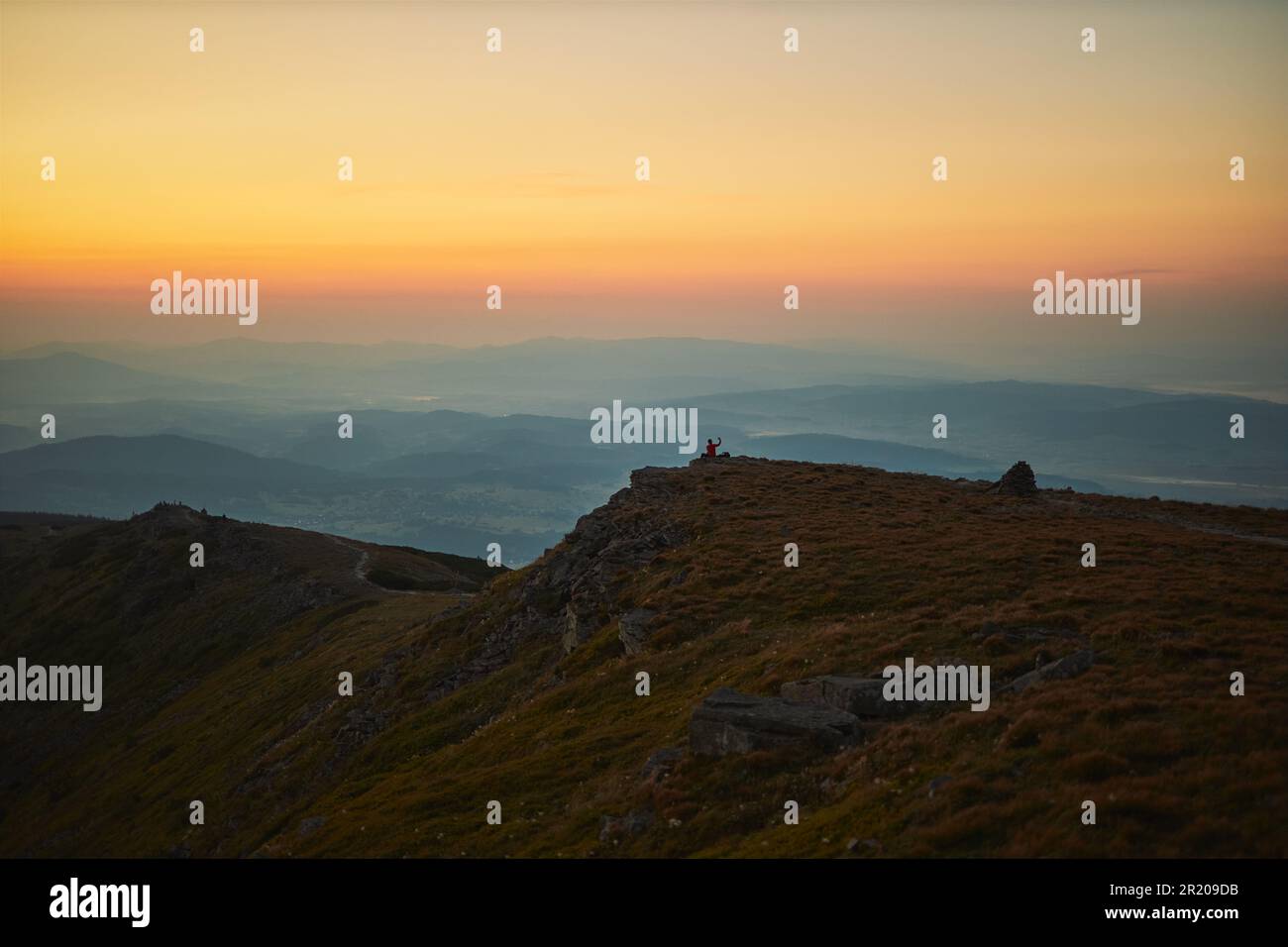 Man looking at sunrise. Mountains at sunrise. Man standing on peak ...