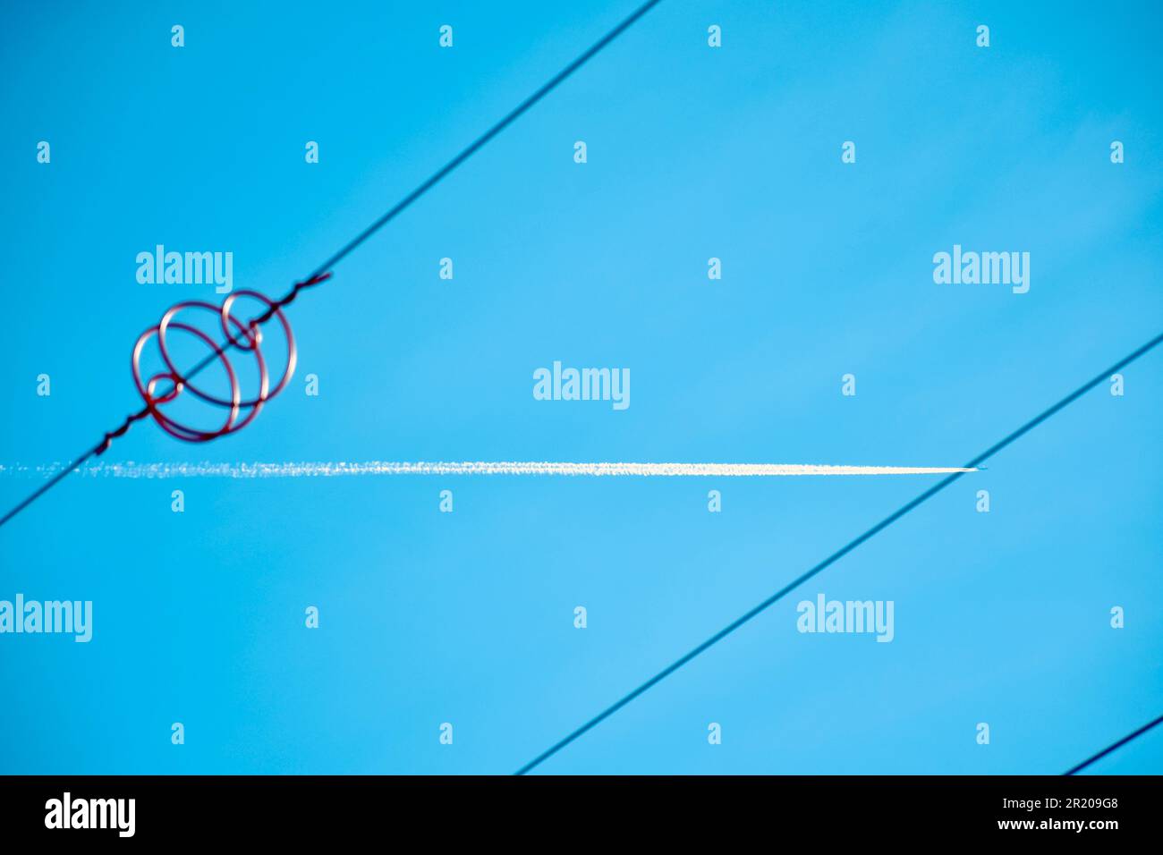 A low angle of an airplane track seen through metal wires Stock Photo ...