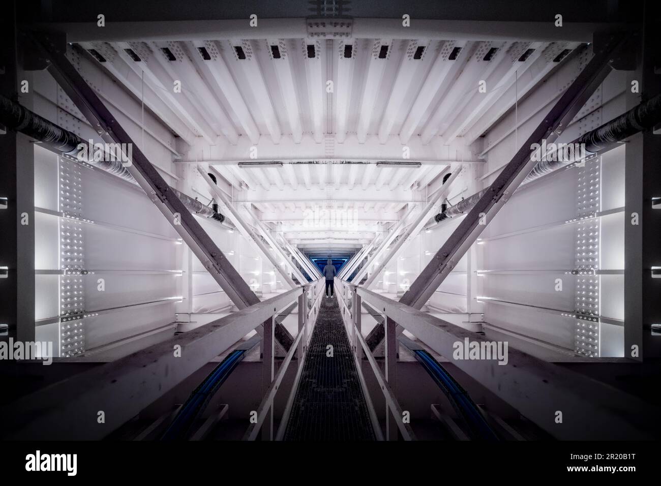 A person standing inside a symmetrical man-made interior walkway with ...