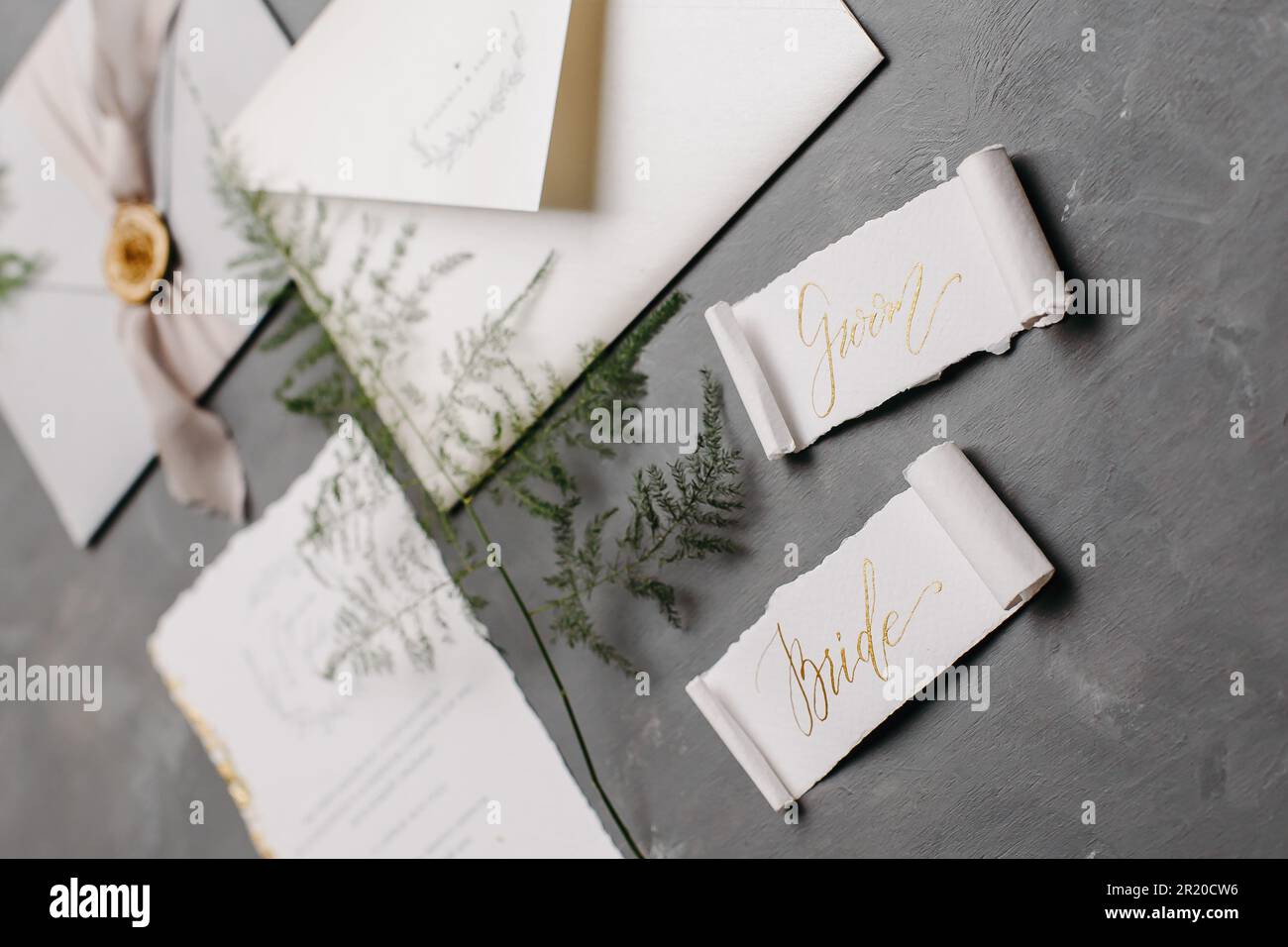 A flat lay of minimalistic wedding invitation details - letters, plant ...