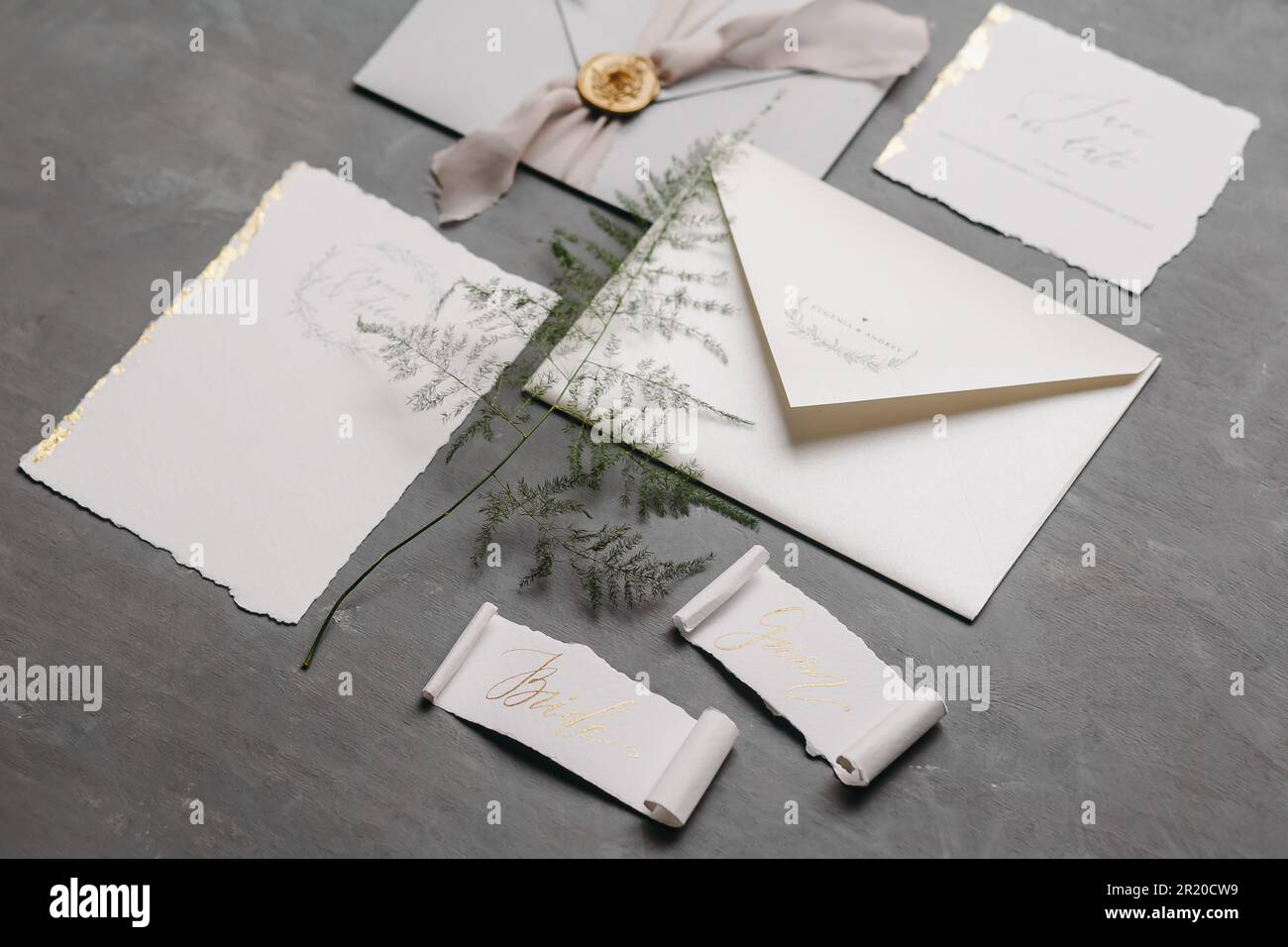 A flat lay of minimalistic wedding invitation details - letters, plant ...