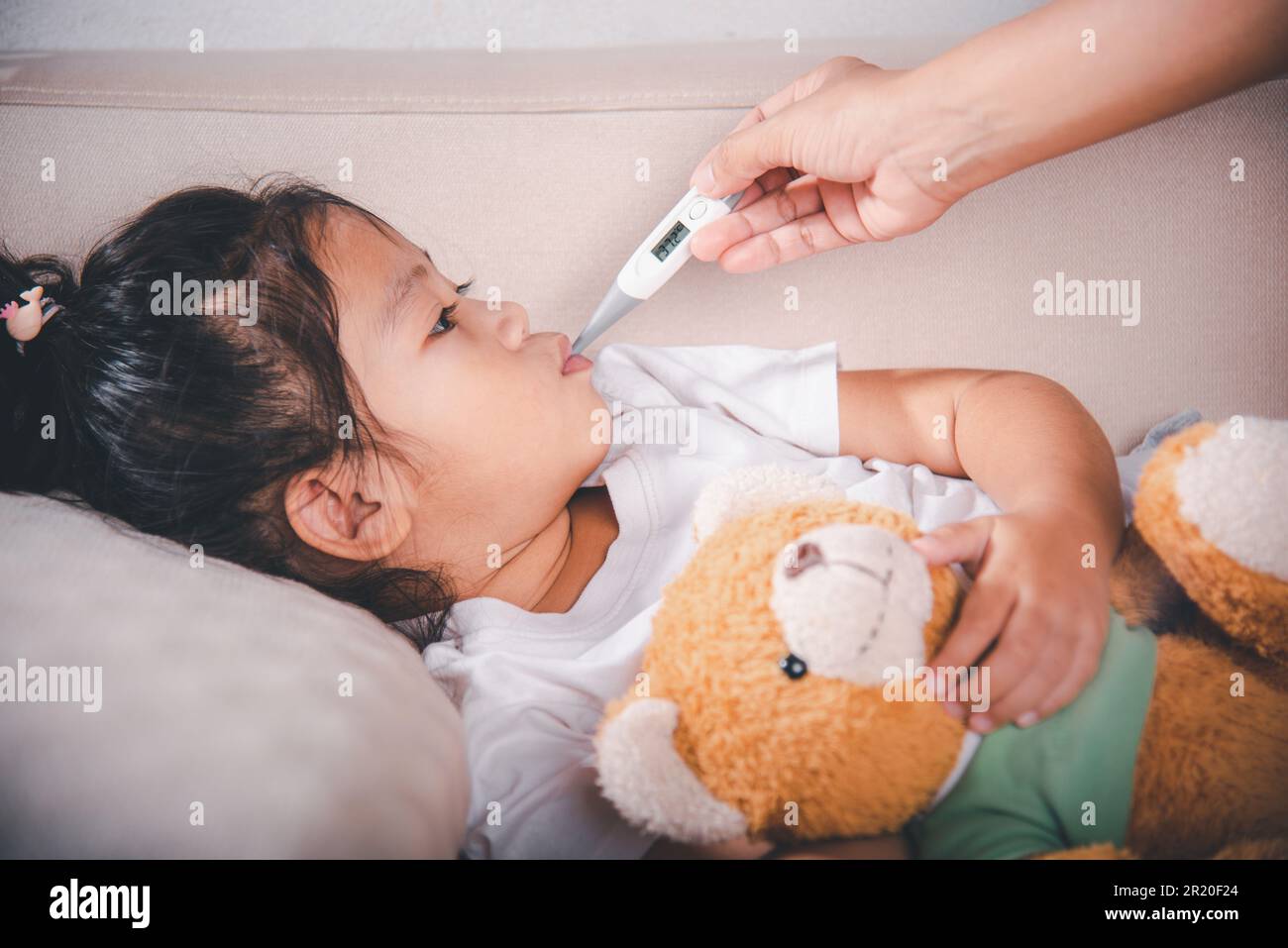 Mother parent checking temperature of her sick daughter with digital thermometer in mouth Stock ...