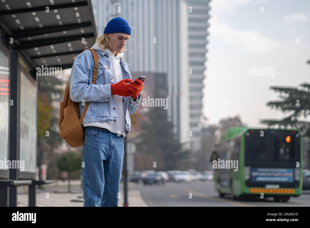 Young man using mobile phone at bus stop hi-res stock photography and ...