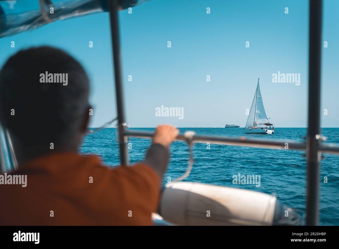 A silhouette of a person gazing from a yacht on a vast ocean with boats ...