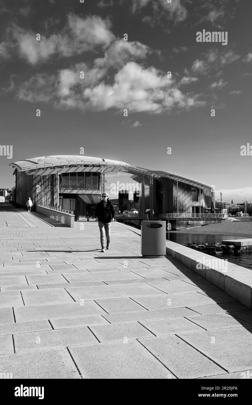 A Vertical Shot Of A Caucasian Adult Male Walking Outside In A City Environment In Black And
