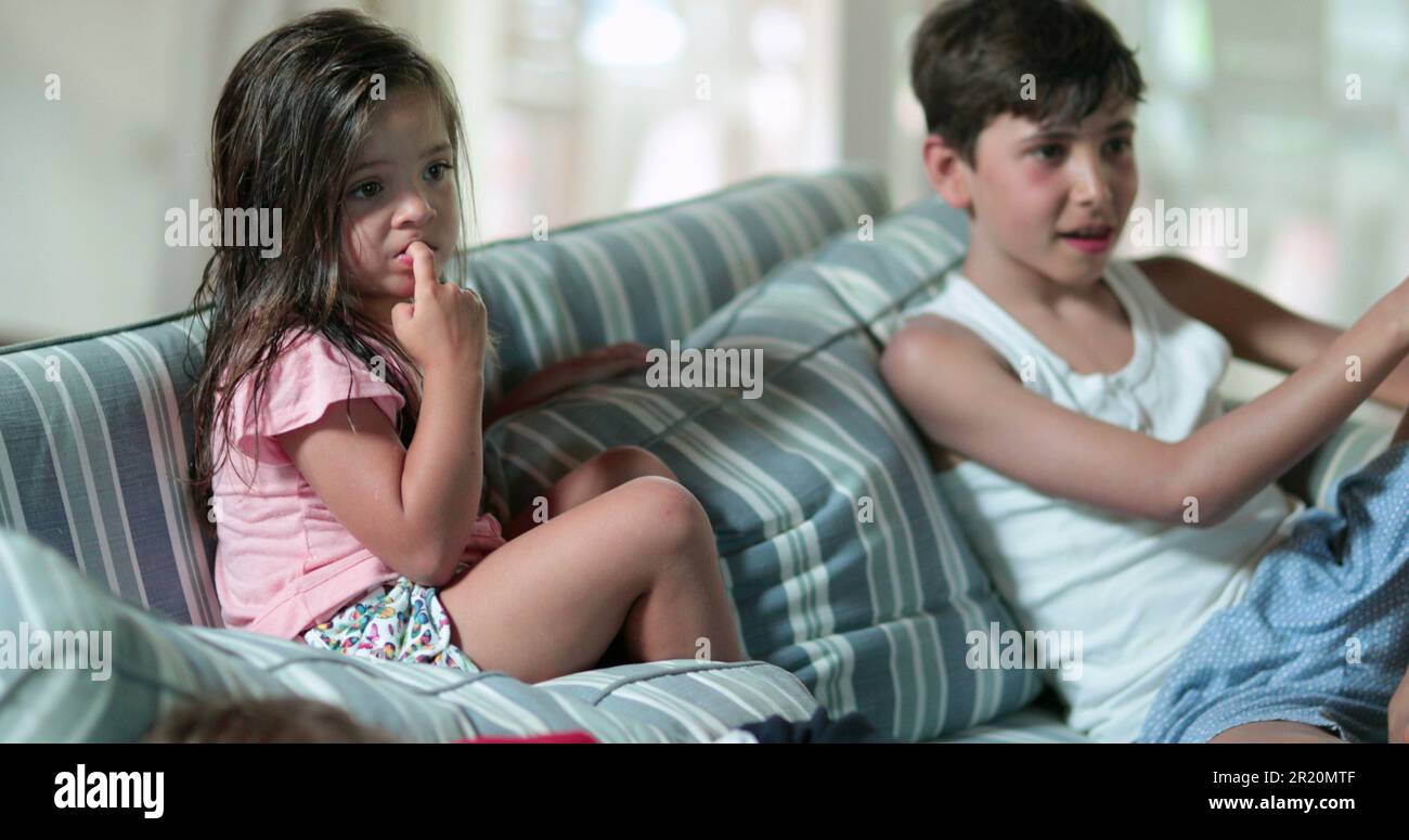 Brother and sister on sofa watching content on tv Stock Photo - Alamy