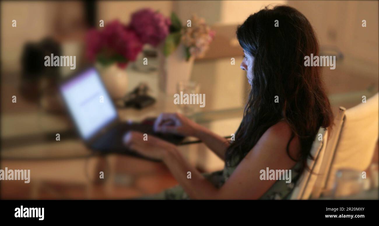 Candid real life woman working late at night in front of screens ...