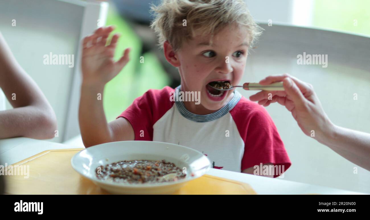 Candid parent feeding supper meal to toddler boy child Stock Photo - Alamy