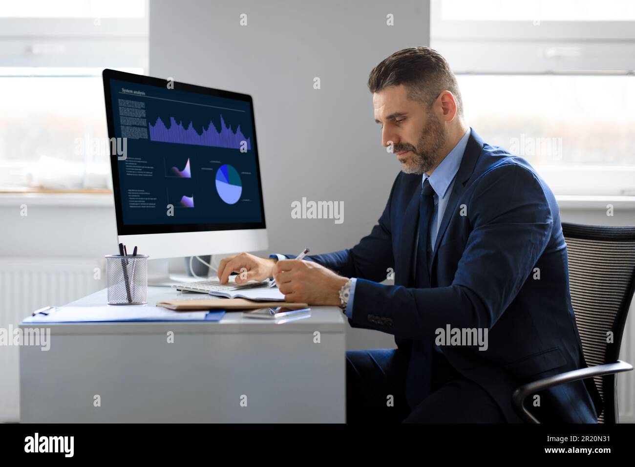 Middle aged businessman working on computer, sitting in front of ...
