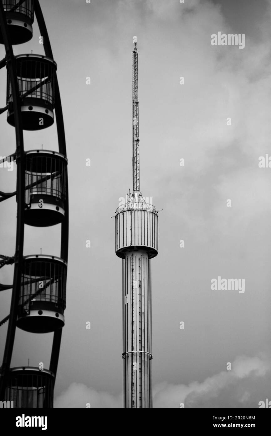A vertical of a tower near a ferris wheel in grayscale Stock Photo - Alamy