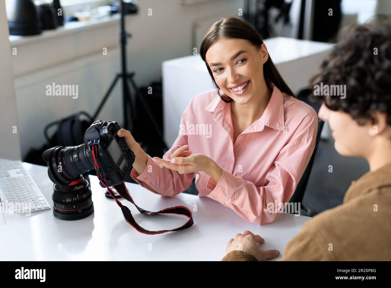 Moments captured. Young photographer woman showing photos work to male ...