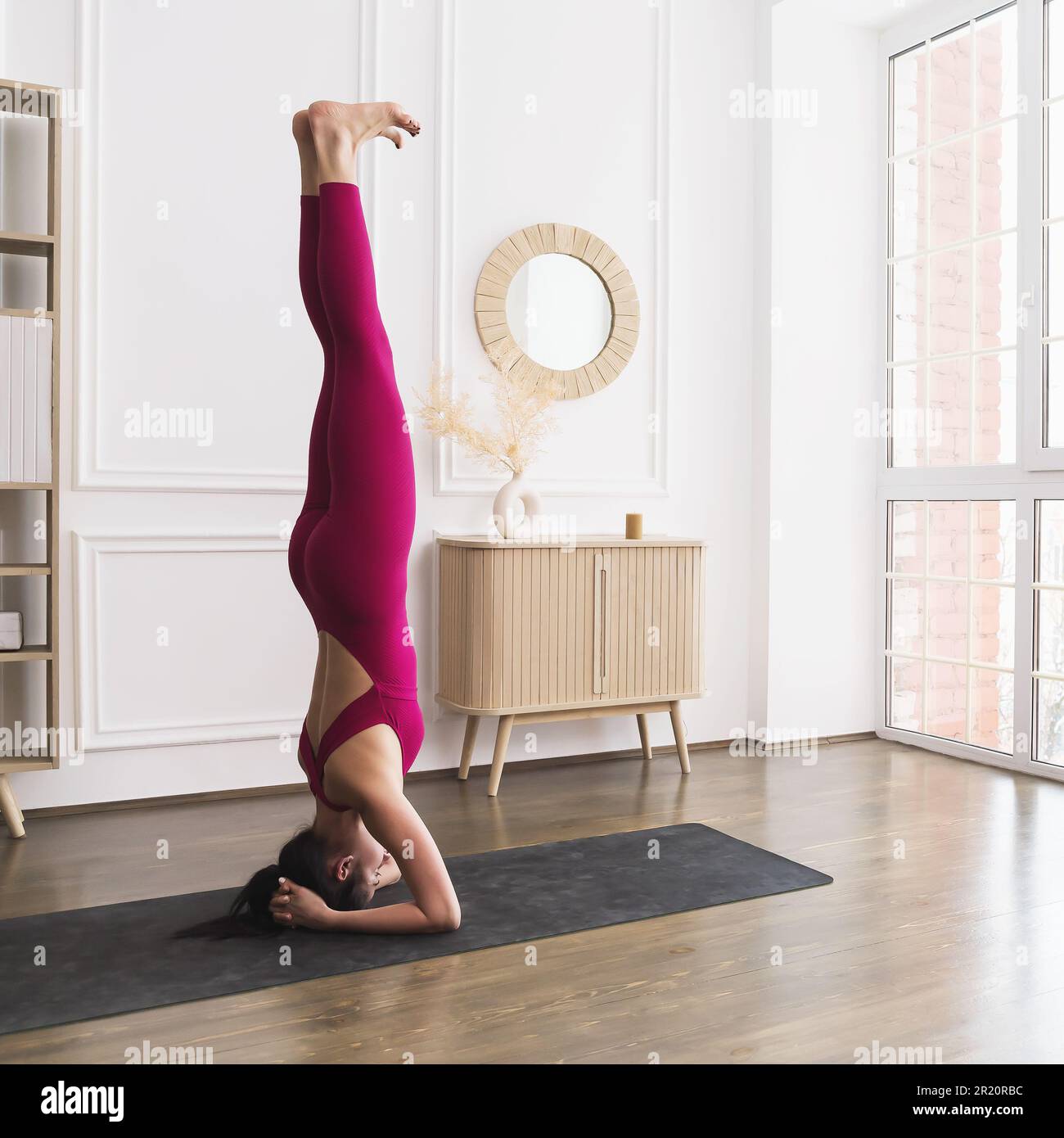 A young woman leading a healthy lifestyle and practicing yoga, performs ...