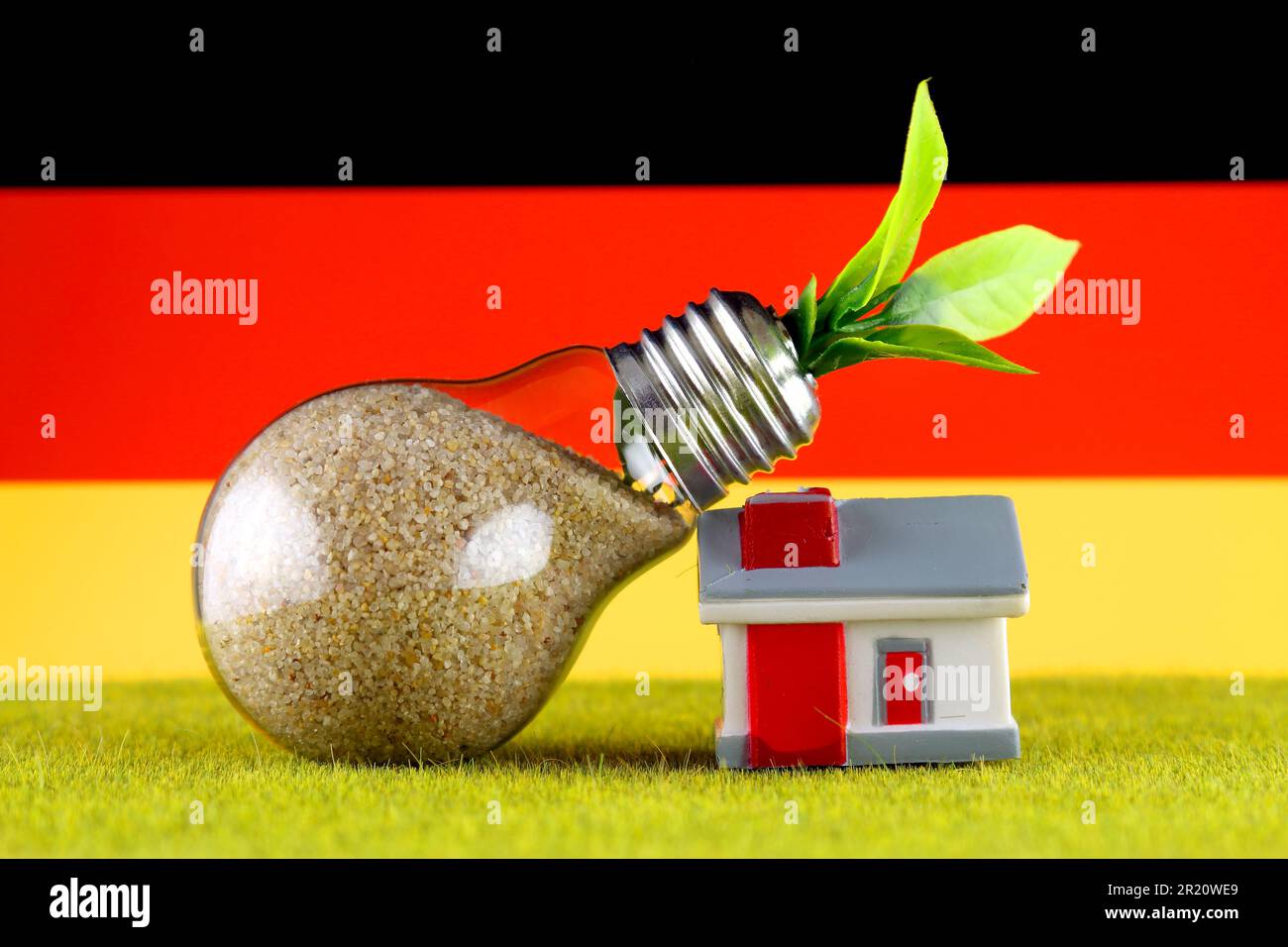 Plant growing inside the light bulb, miniature house on the grass and ...