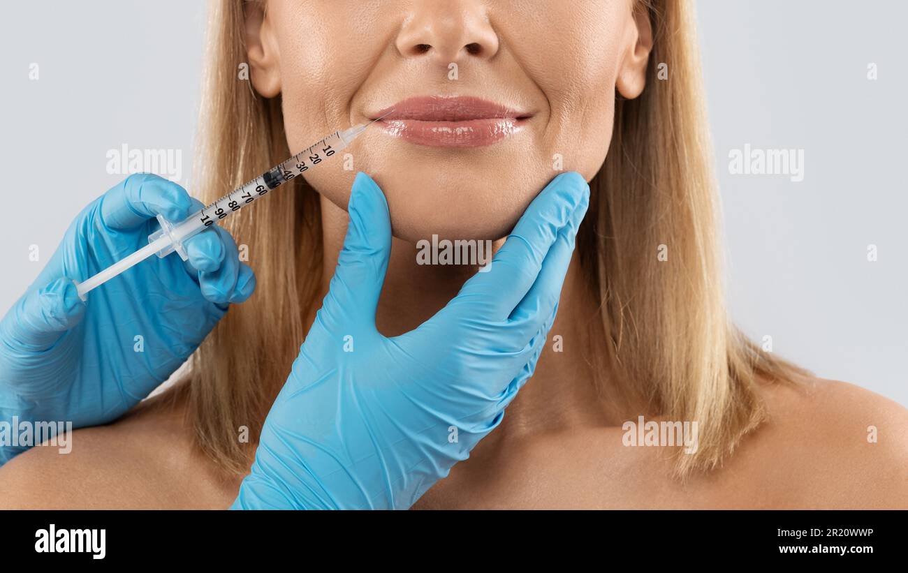 Unrecognizable middle aged lady getting beauty injection in her lips ...
