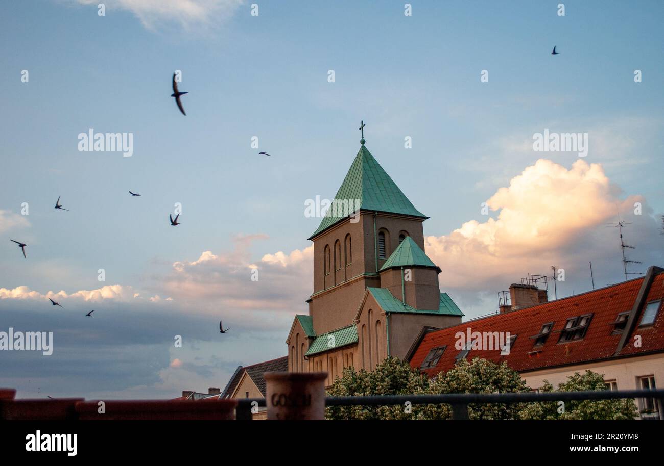 The Holy Trinity Catholic Church with birds flying in the blue sky ...