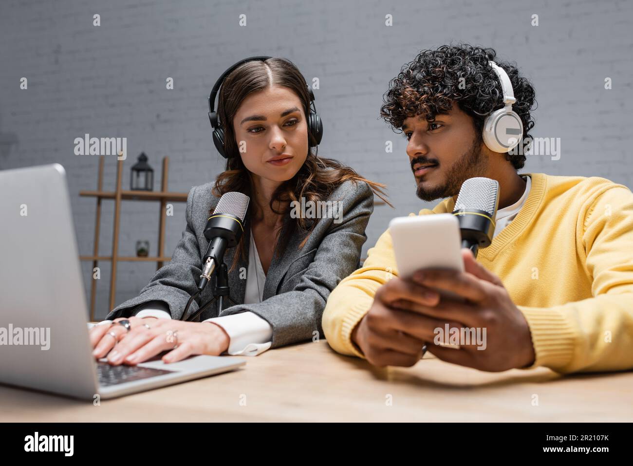 charming brunette podcaster in headphones and grey blazer using laptop ...