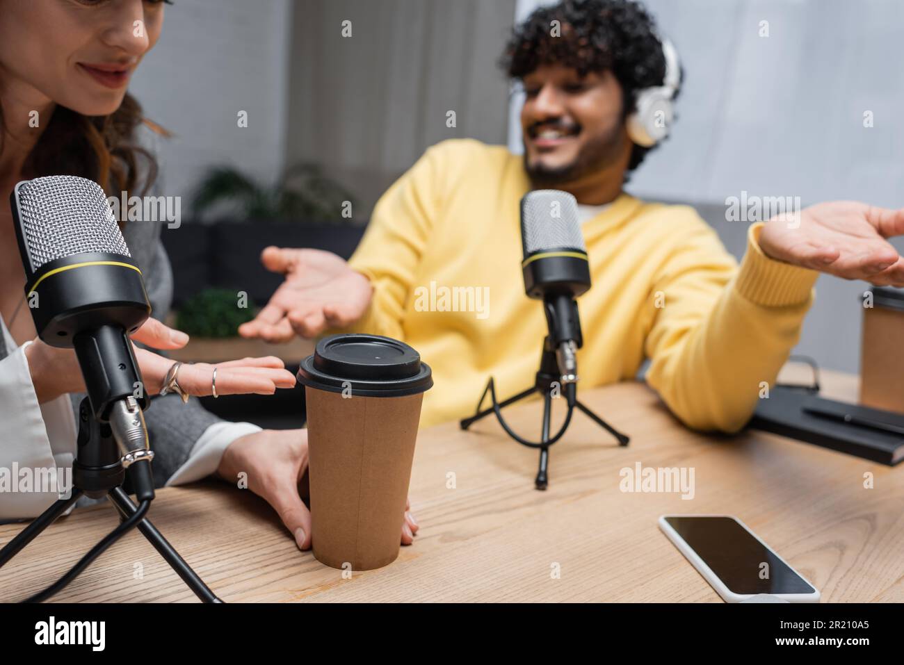radio host pointing at takeaway drink near studio microphones ...