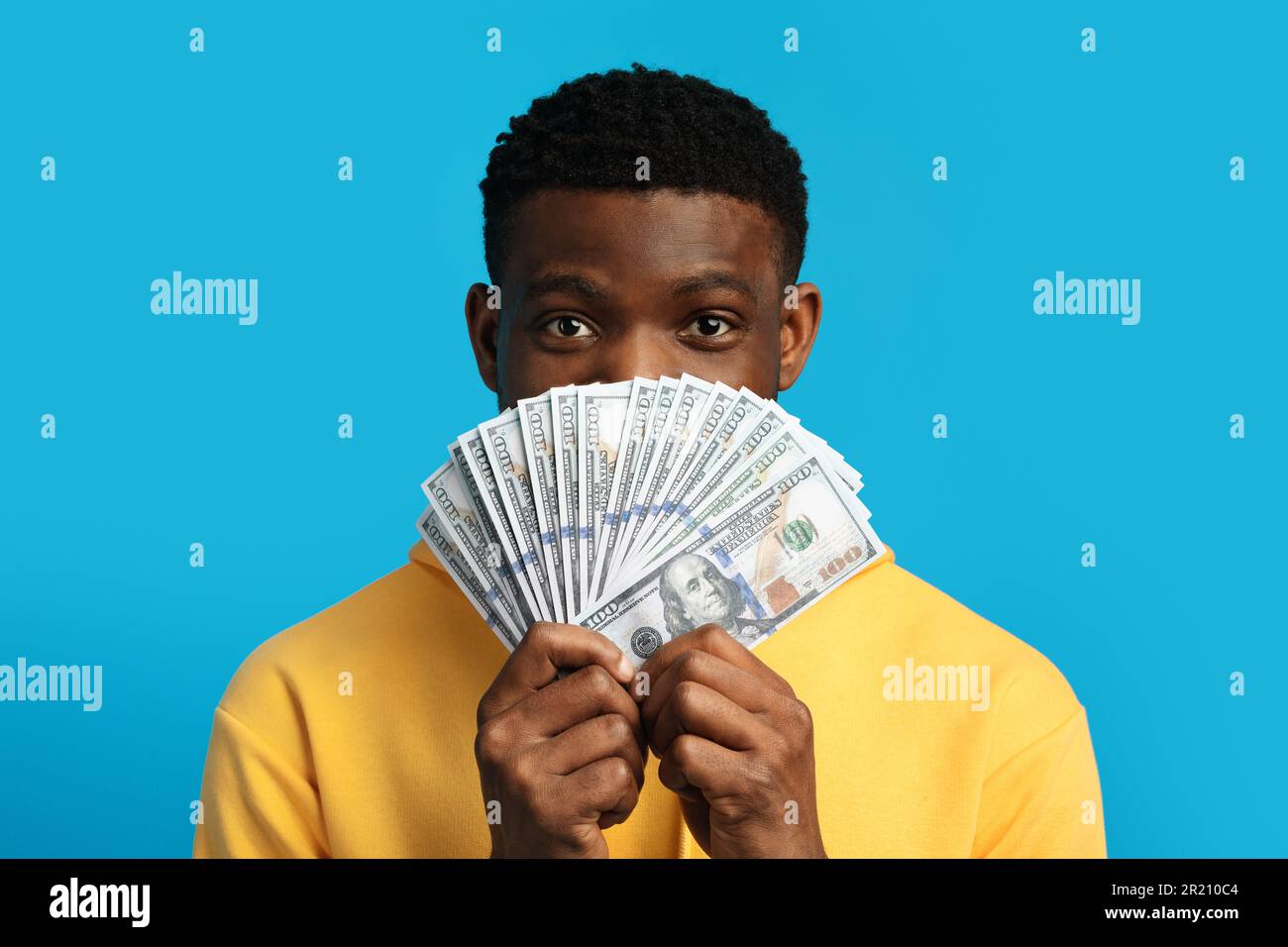 Black guy holding money cash over his face, blue background Stock Photo ...