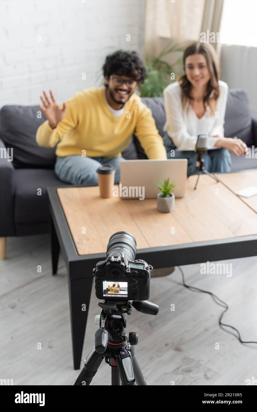 blurred indian man waving hand during video chat on laptop near smiling ...