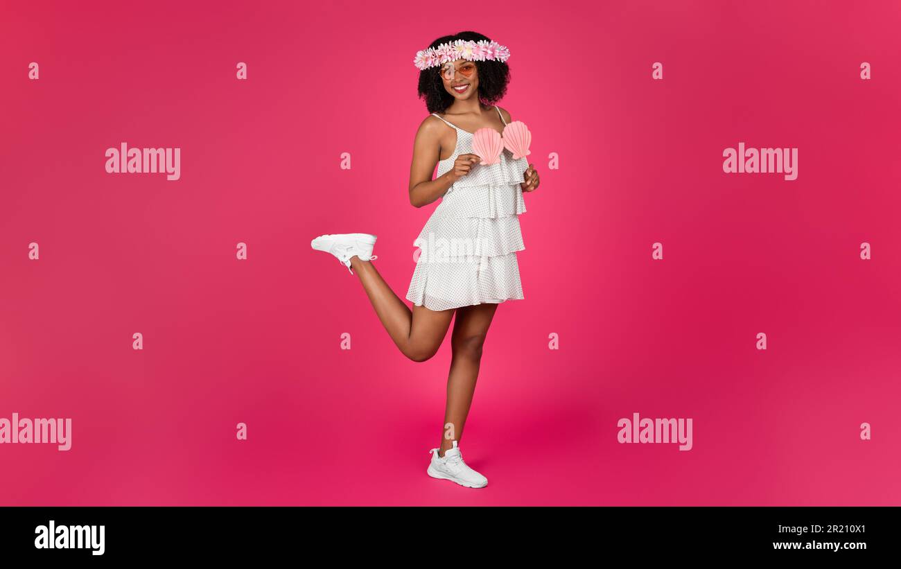 Satisfied young black curly woman in dress and sneakers, sunglasses and ...