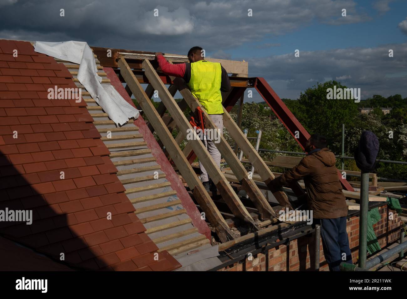 Roofing construction work showing building worker in a green hi vis ...