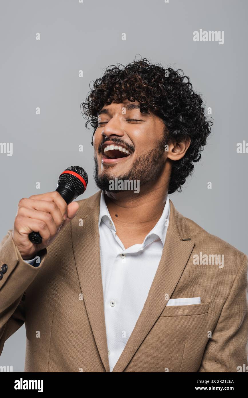 Portrait of cheerful indian event host with closed eyes in formal wear ...