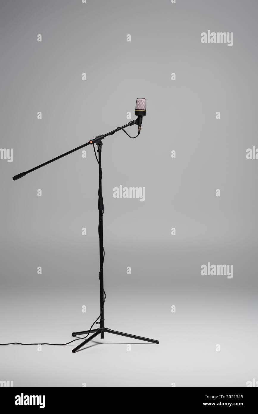 Black microphone with wire on stand on grey background with copy space ...