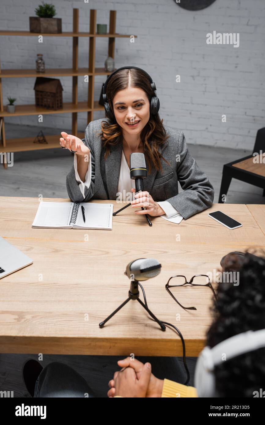 smiling and charming announcer in headphones talking and gesturing near ...