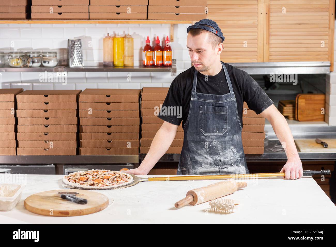 The chef prepares pizza. Raw pizza ready to bake. Cook in a blue apron ...