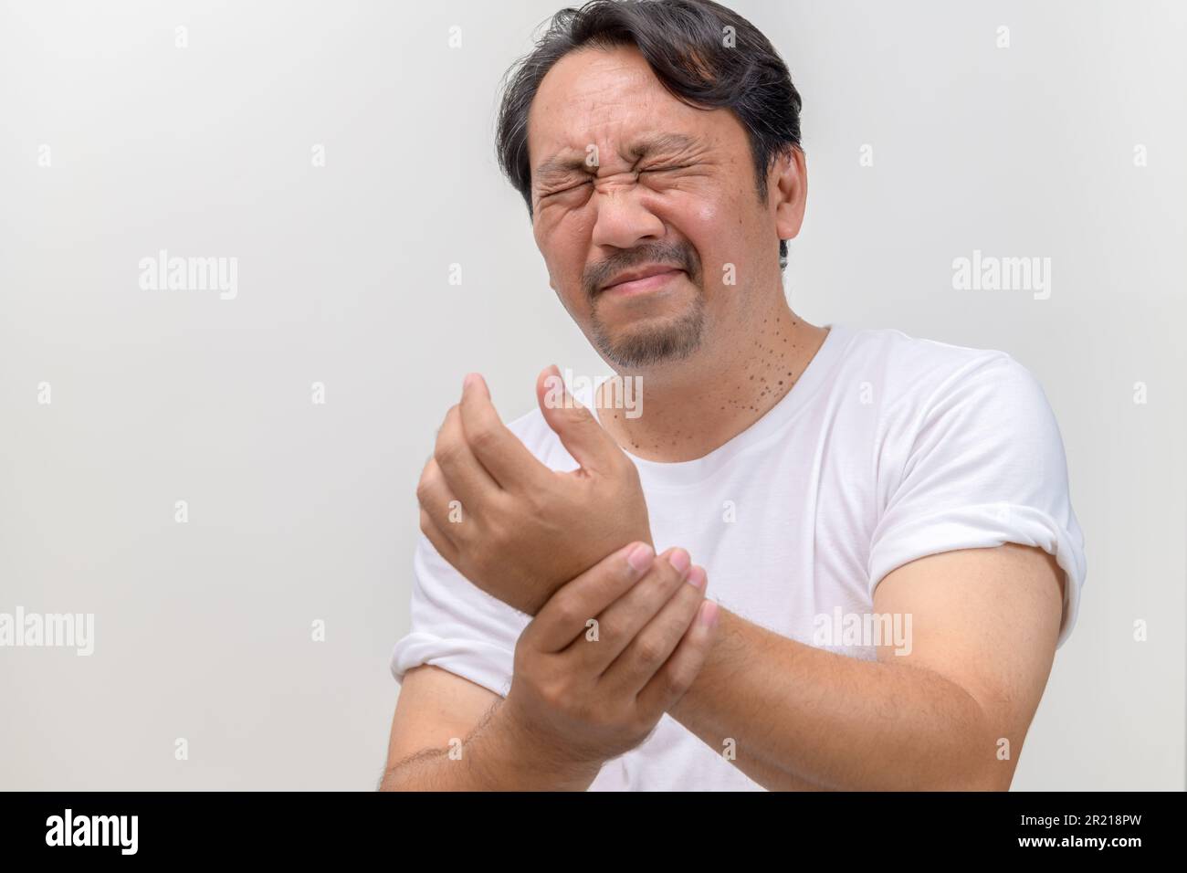 A bearded man is seen suffering from a wrist injury isolated on white ...