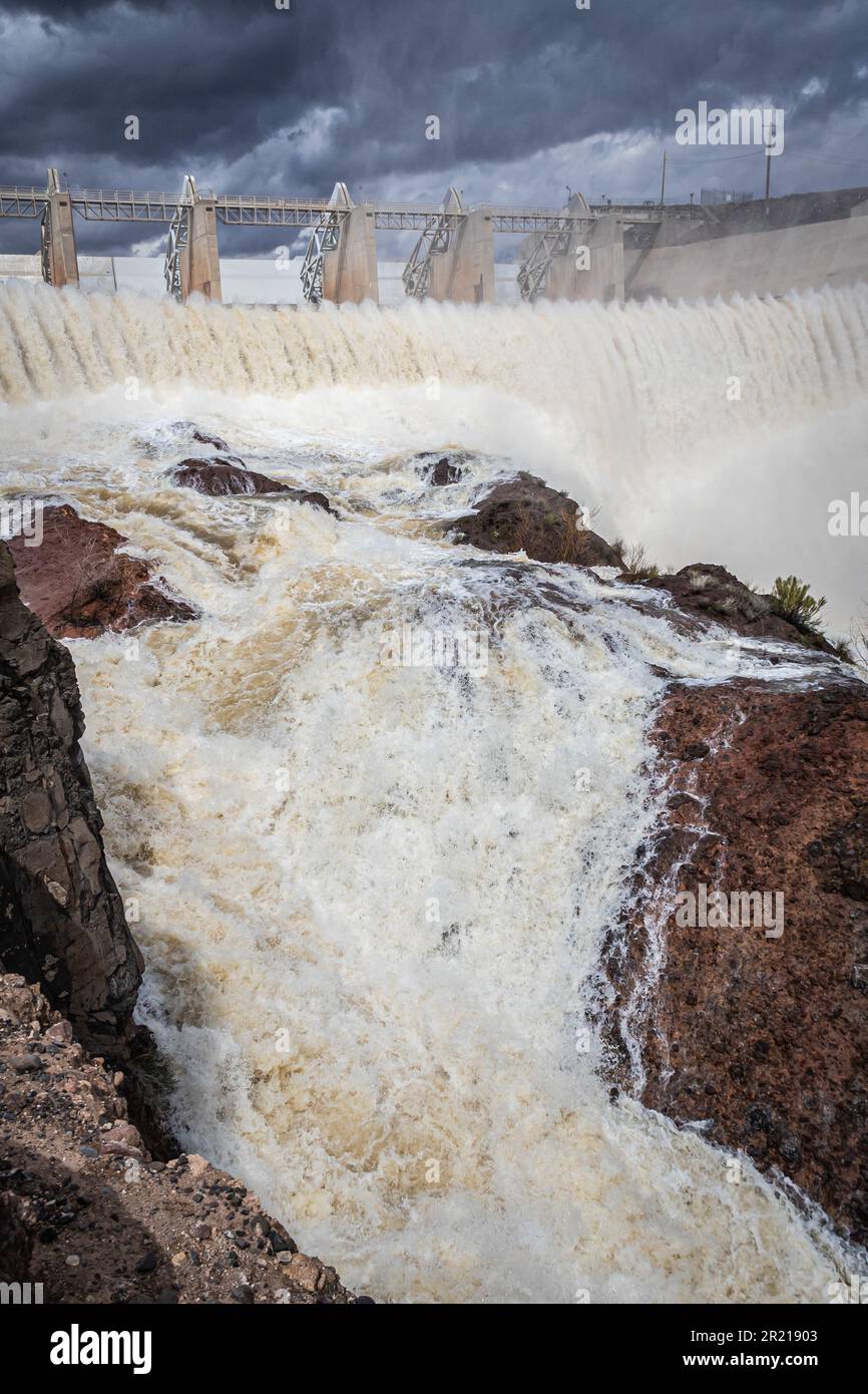A dam with its flood gates open and a large volume of water flowing ...