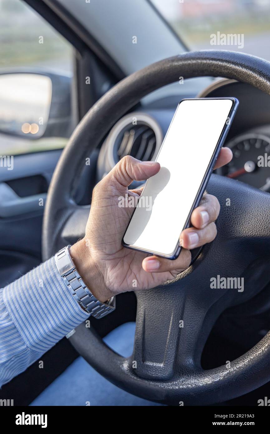Detail of the hand of a driver holding a mobile phone with a blank ...