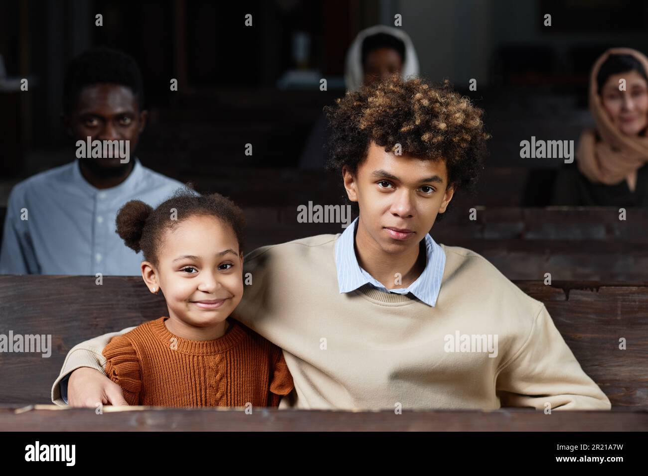 Portrait of brother and sister sitting on bench in baptist church with ...
