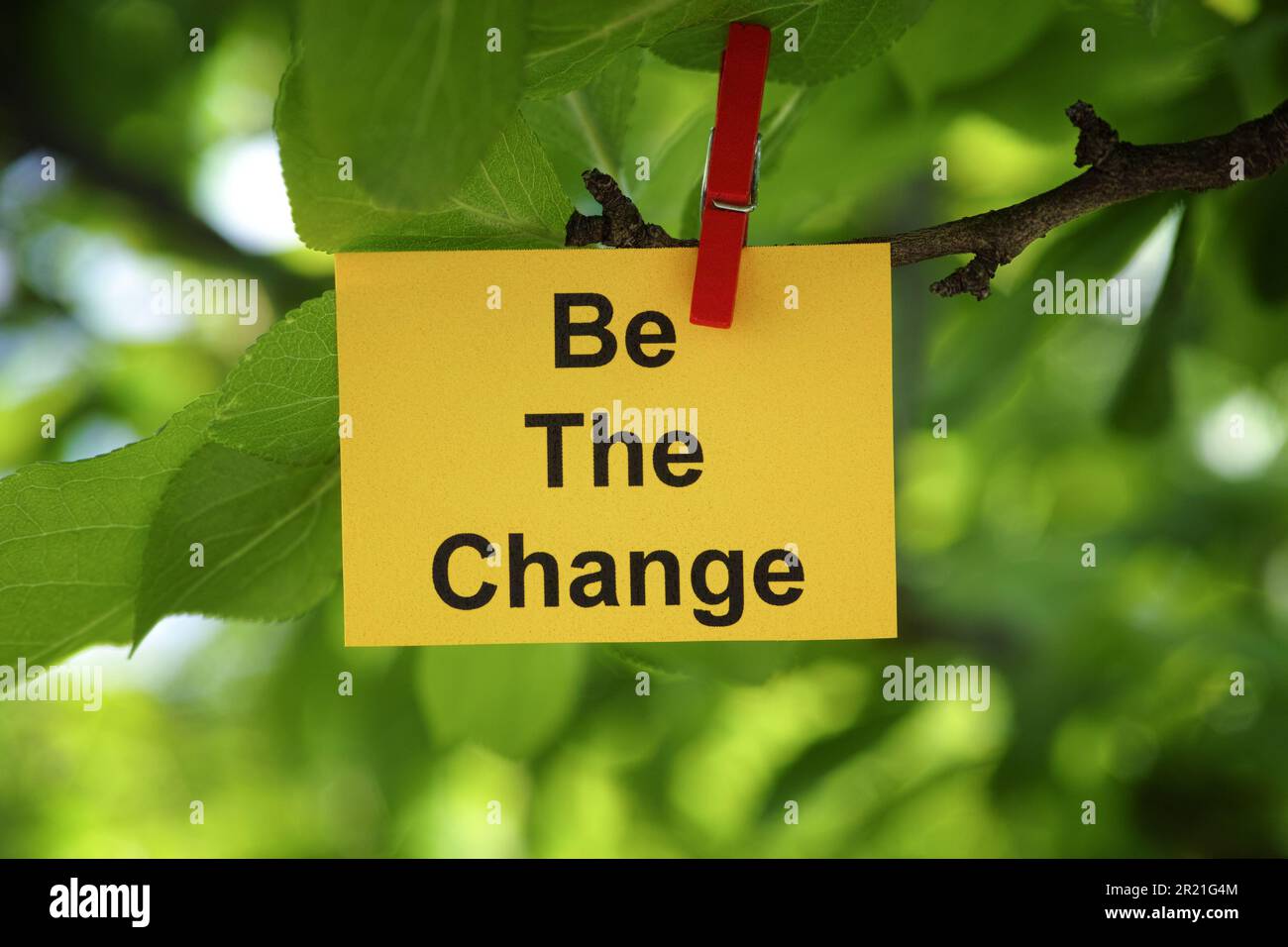 A yellow paper note with the phrase Be The Change on it attached to a ...