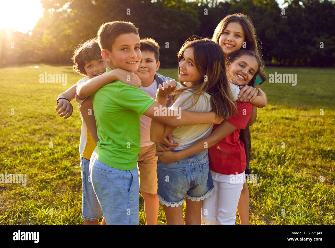 Group of friendly cheerful children standing in circle and hugging each ...