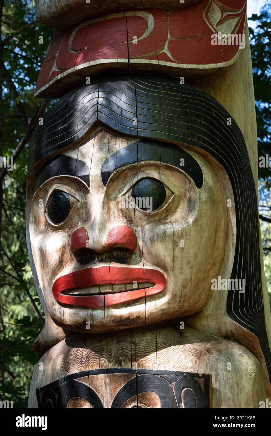 An indigenous totem pole situated in a lush and dense forest landscape ...