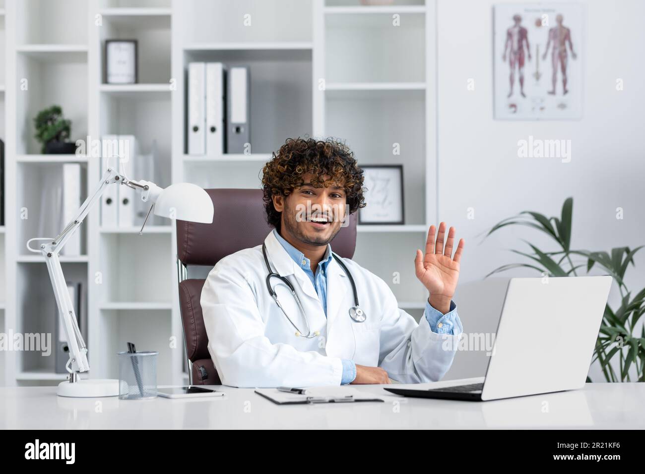 Smiling young Hispanic male doctor student, intern, assistant sitting ...