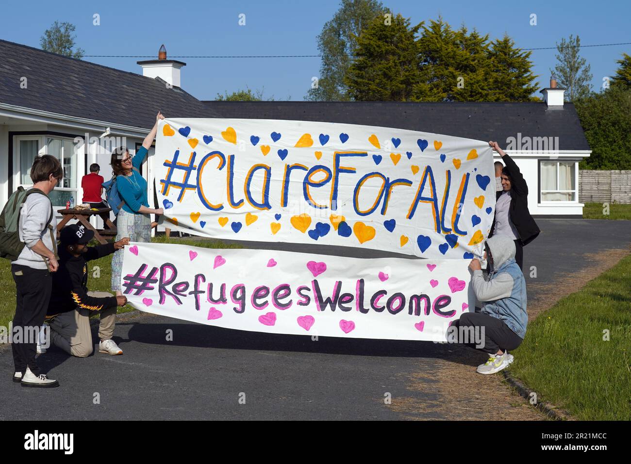 Local residents with asylum seekers hold up a banner supporting ...