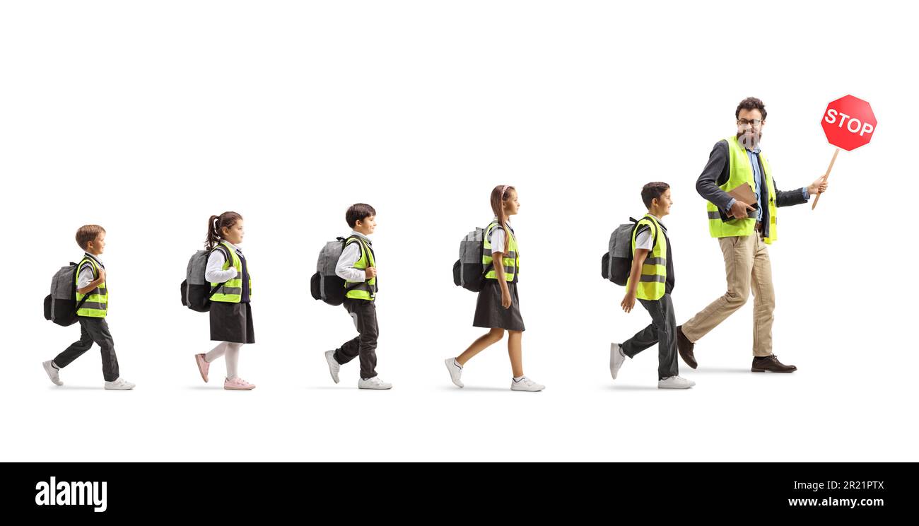 Male teacher leading schoolchildren in safety vests across street and ...