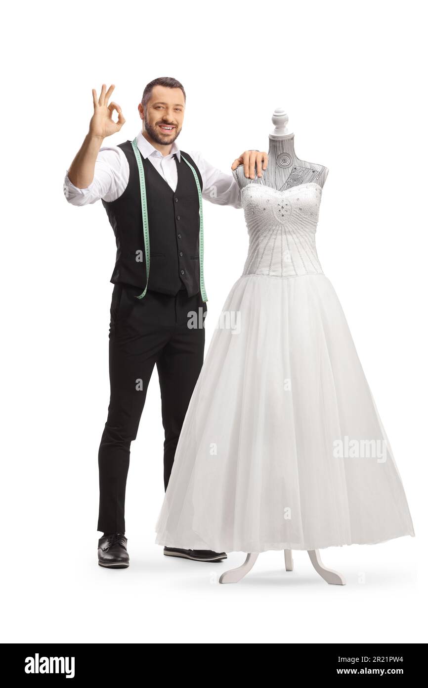 Tailor standing next to a bridal gown on a doll mannequin and gesturing ...