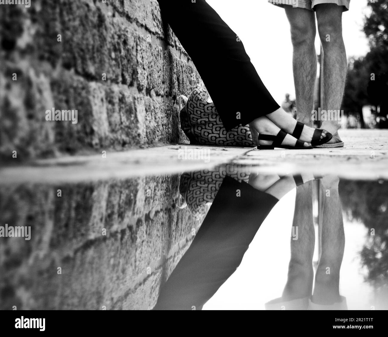 two people reflecting in a puddle of rainwater Stock Photo - Alamy