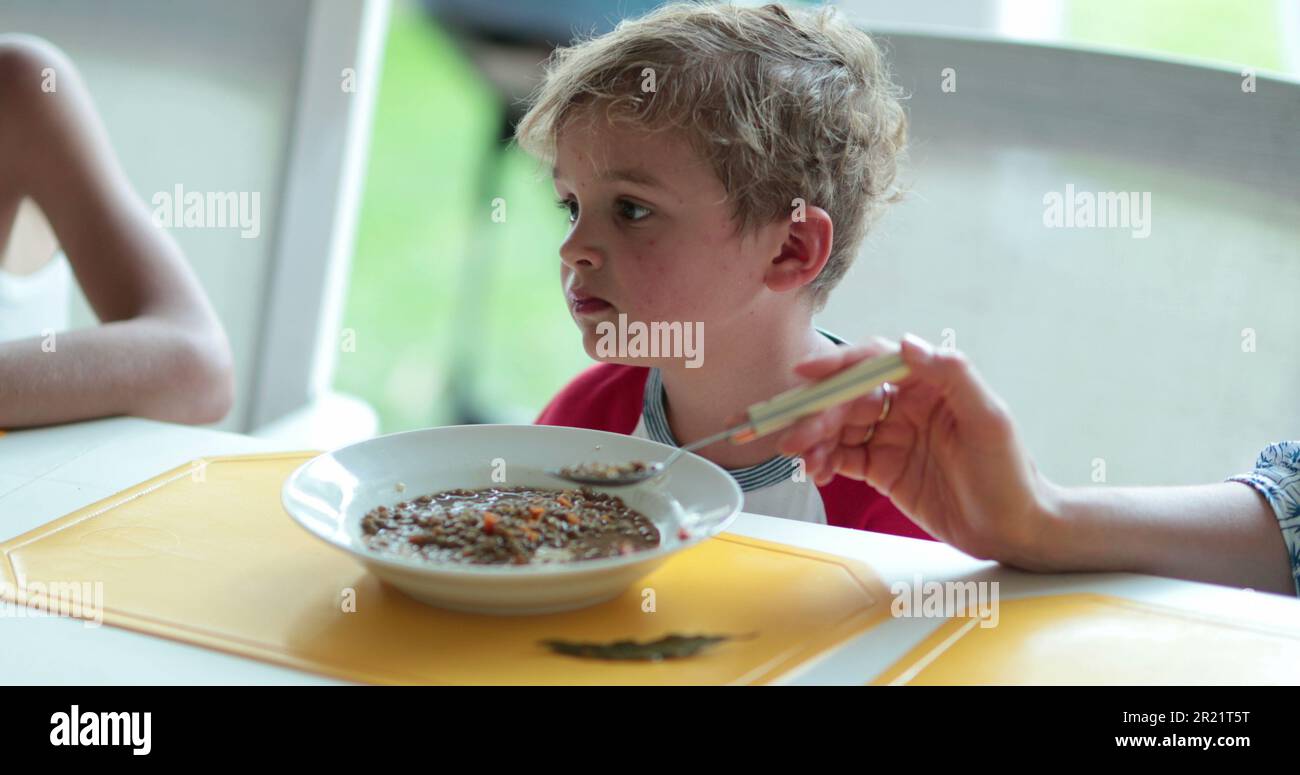 Child boy seated at meal table feeding supper Stock Photo - Alamy