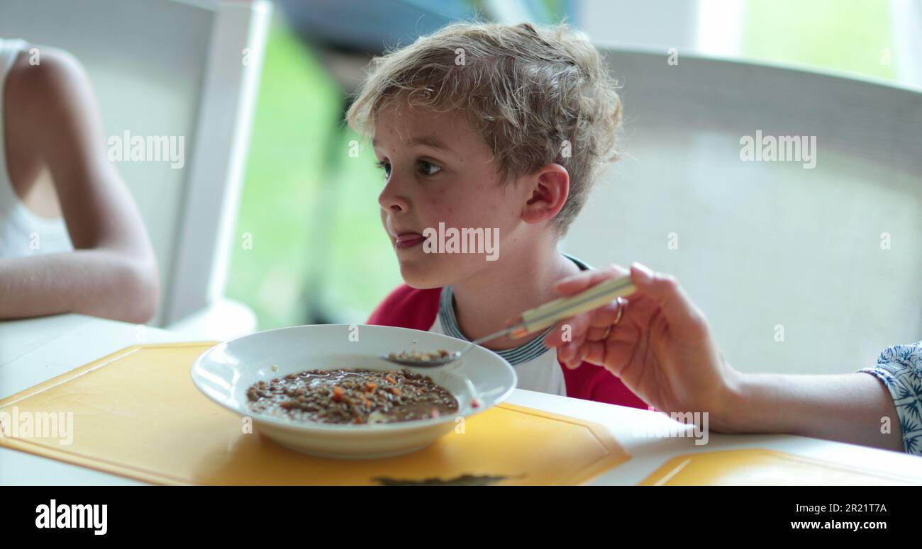 Child boy seated at meal table feeding supper Stock Photo - Alamy
